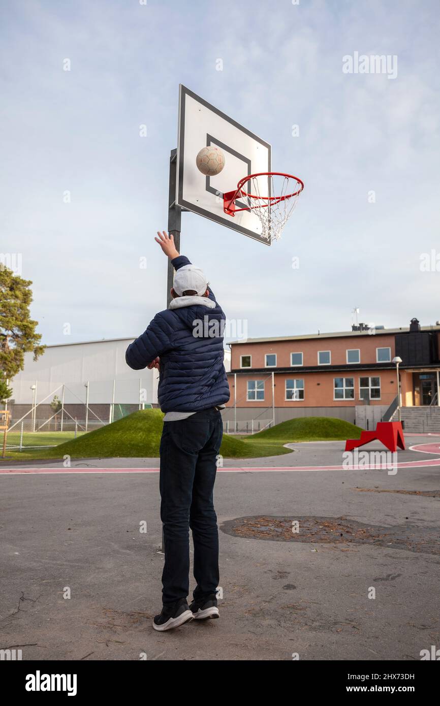 Rear view of teenage boy shooting basketball Stock Photo - Alamy