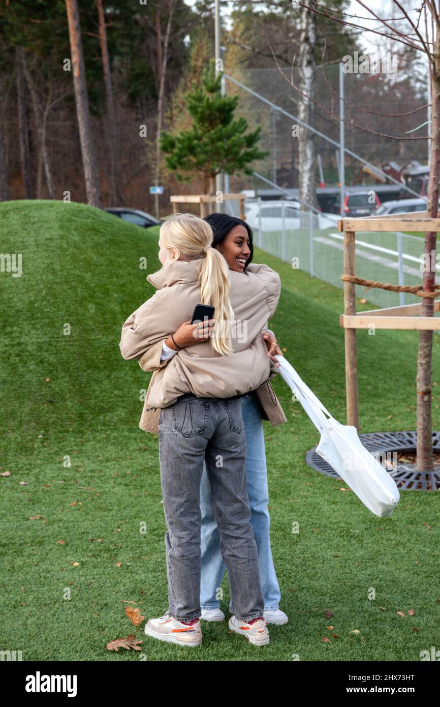 Teenage girl friends hugging outdoors Stock Photo - Alamy