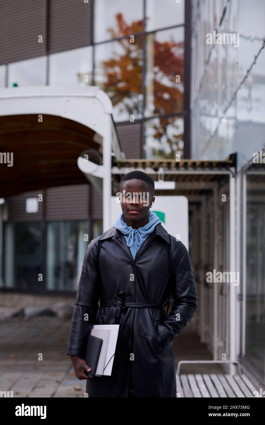 Young man standing in front of modern building Stock Photo - Alamy