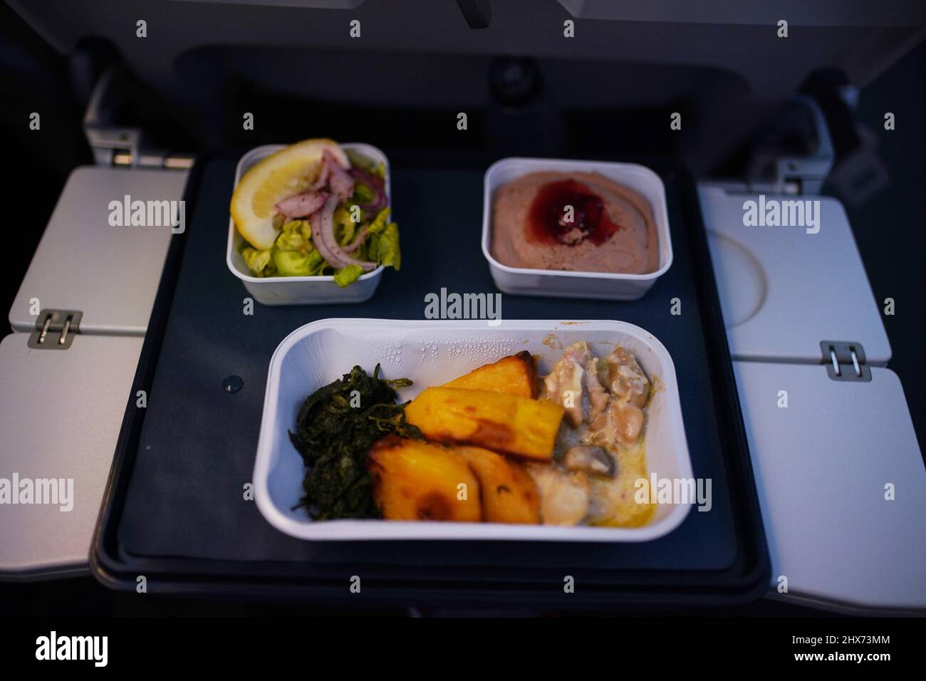A chicken airline meal is placed on a passenger's tray, in the cabin of ...