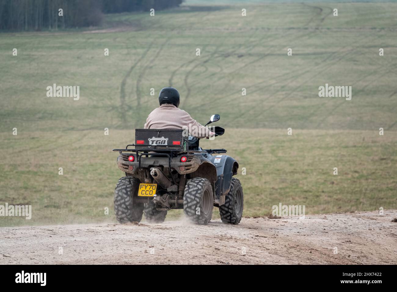 a quad biker with lights on riding his off-road quad bike along a stone ...