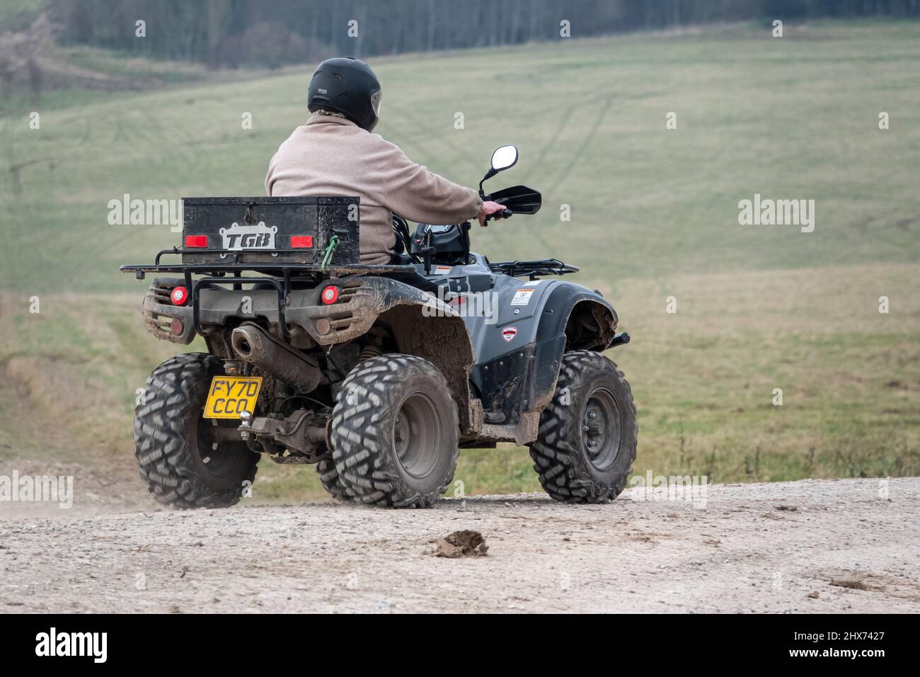 a quad biker with lights on riding his off-road quad bike along a stone ...