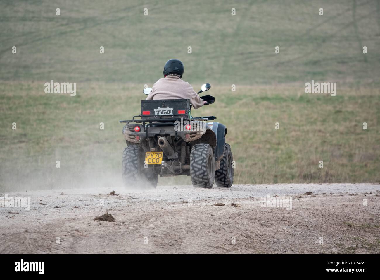 a quad biker with lights on riding his off-road quad bike along a stone ...