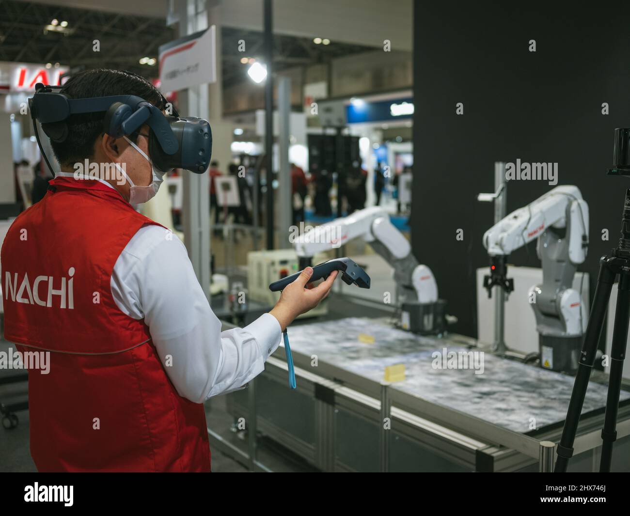 A staff from Japans maker Nachi uses VR devices to control robotic arm ...