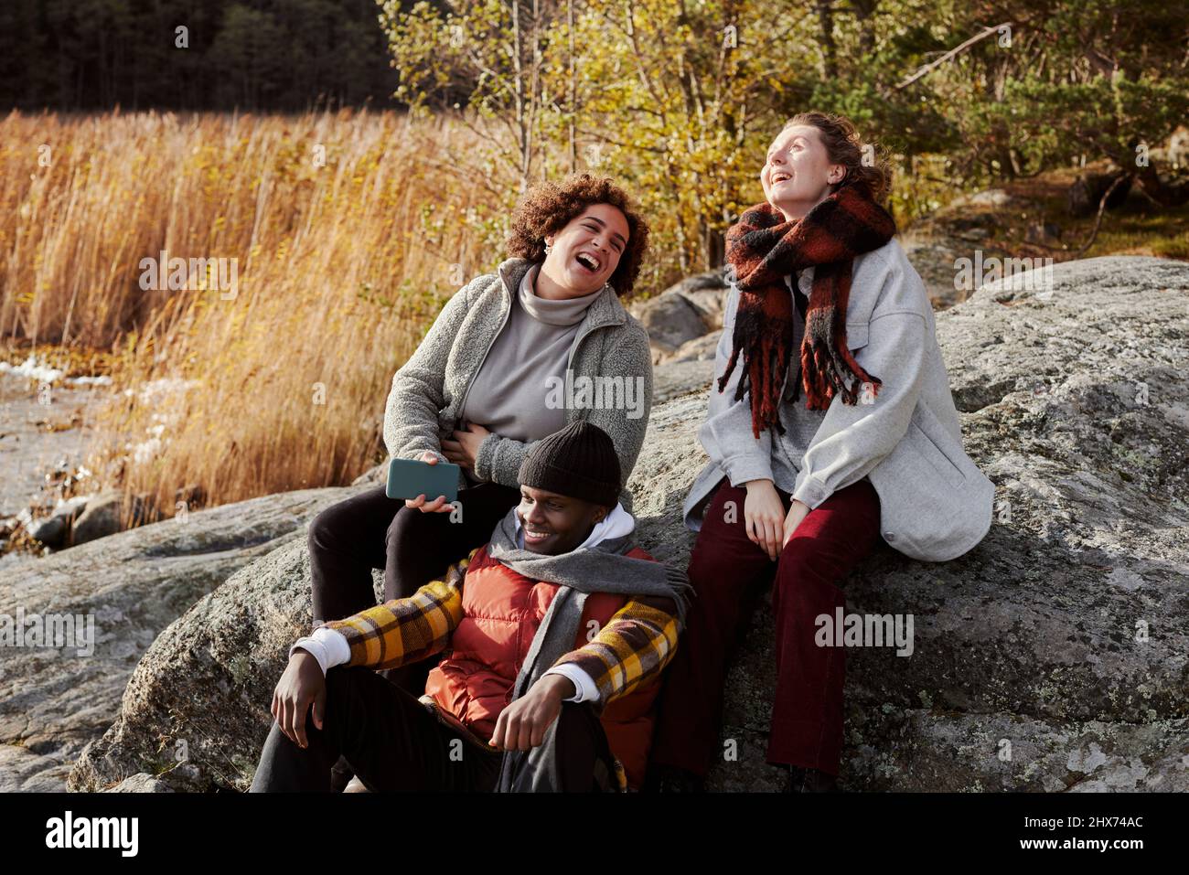 Group of friends sitting on rocks and laughing Stock Photo - Alamy