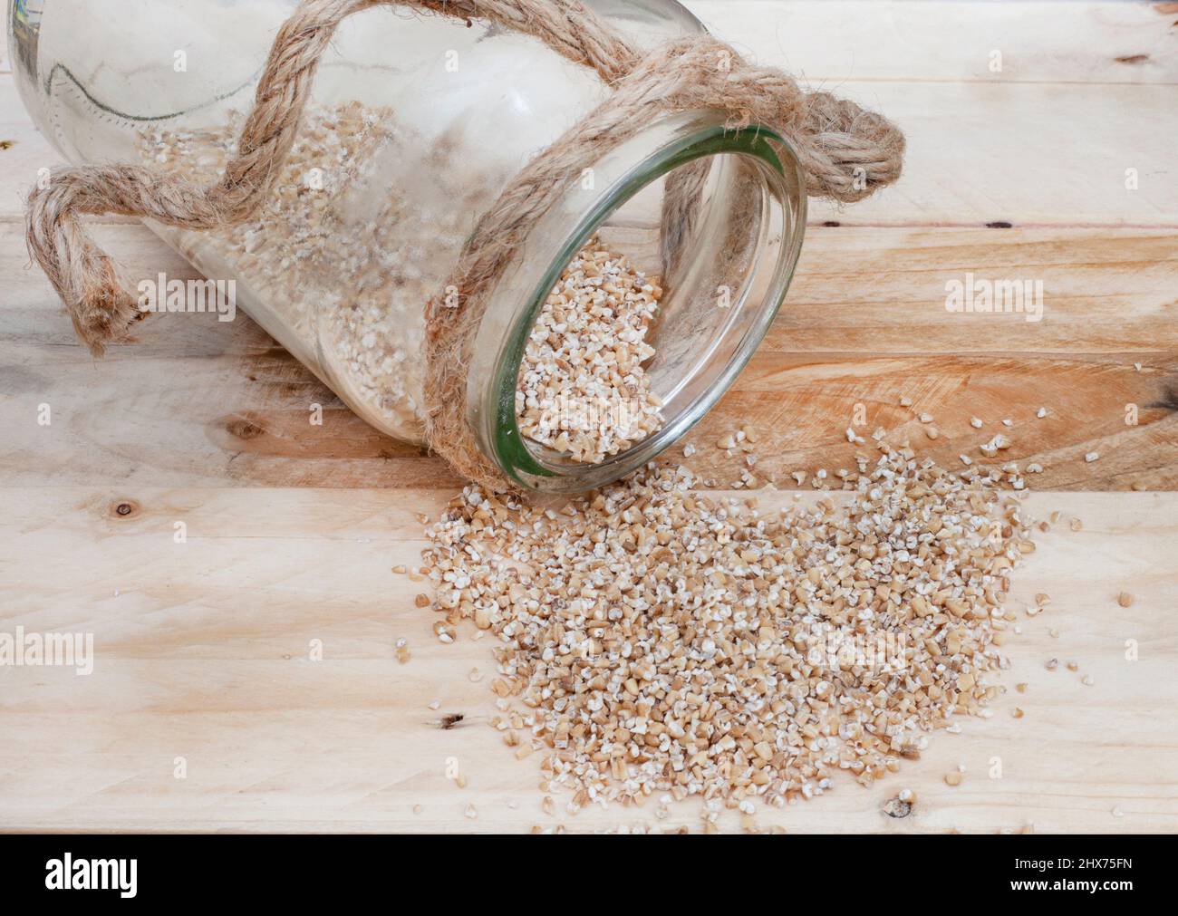 steel cut oats spilling out of almost empty jar on rustic wooden table ...