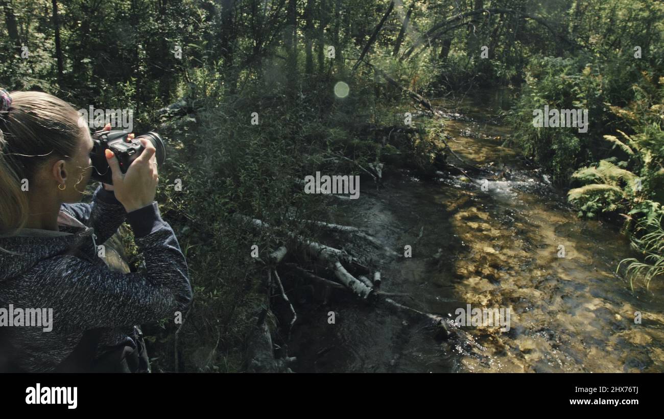 Traveler photographing scenic view in forest river. Wood bridge fallen ...