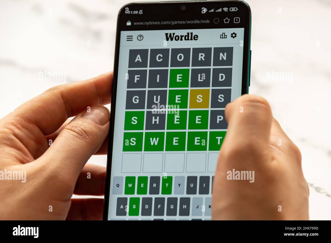 Hands playing Wordle game on phone on NYTimes.com website. Wordle is a ...