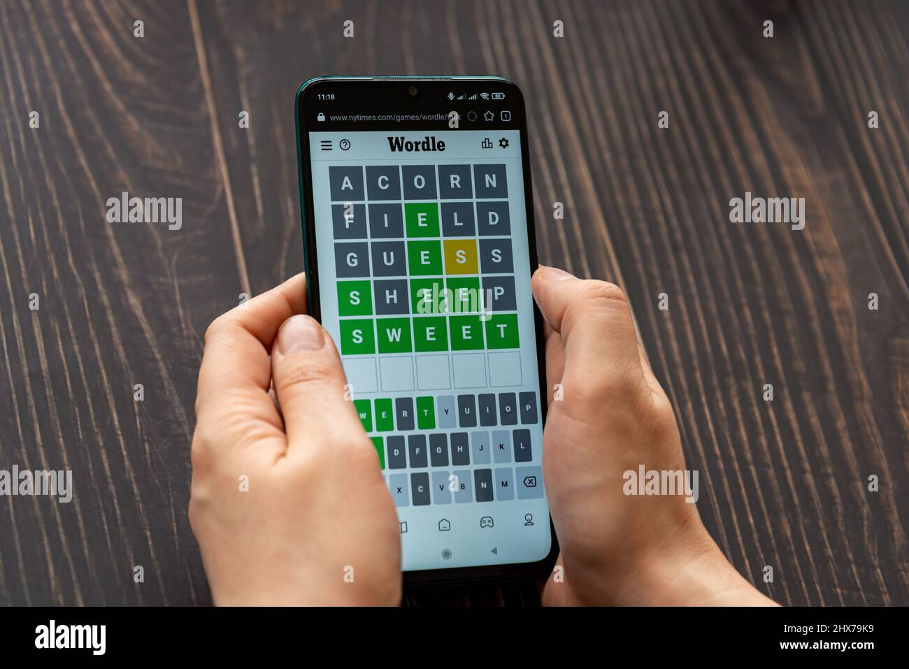 Hands playing Wordle game on phone on NYTimes.com website. Wordle is a ...