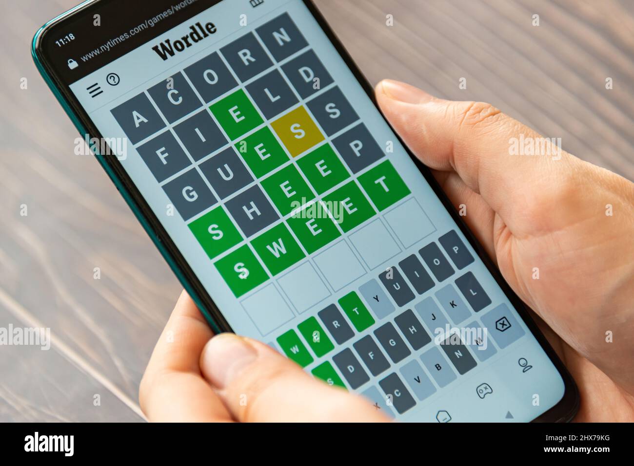 Hands playing Wordle game on phone on NYTimes.com website. Wordle is a ...
