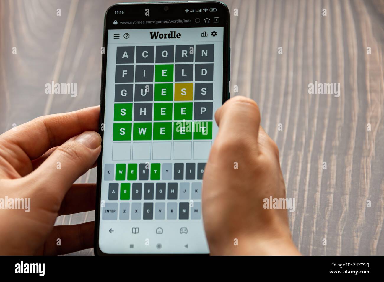 Hands playing Wordle game on phone on NYTimes.com website. Wordle is a ...
