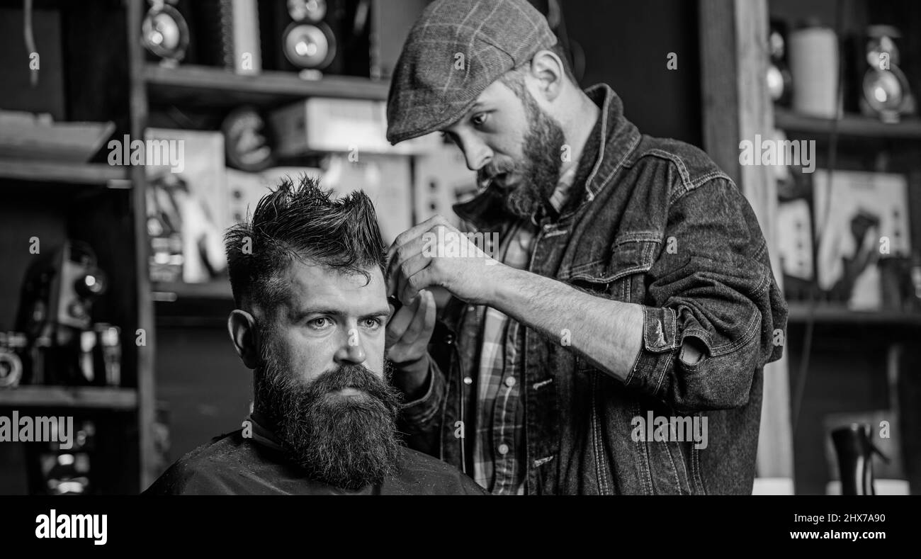 Barber in denim jacket busy with trimming hipster, barbershop ...
