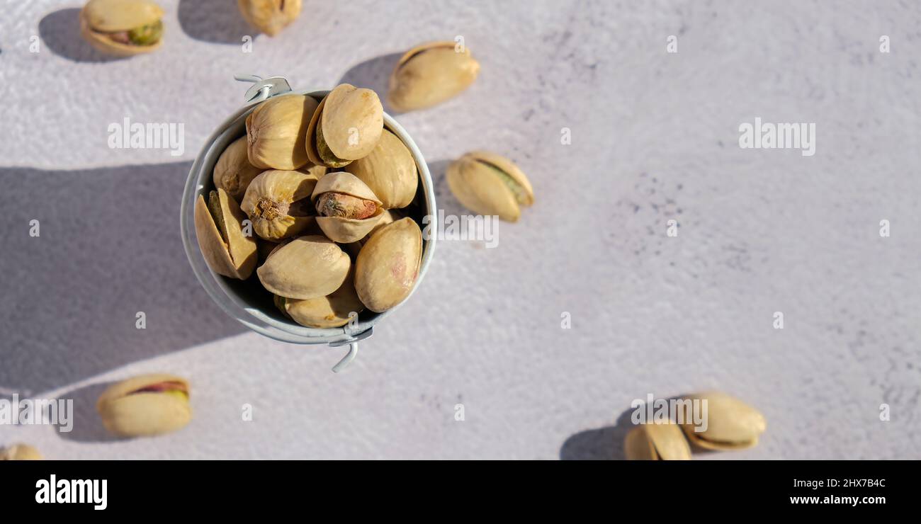 Pistachios in white bucket on concrete background. Healthy and dietary ...