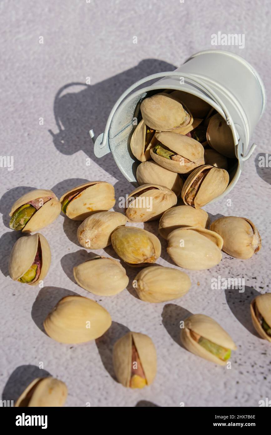 Pistachios in white bucket on concrete background. Healthy and dietary ...