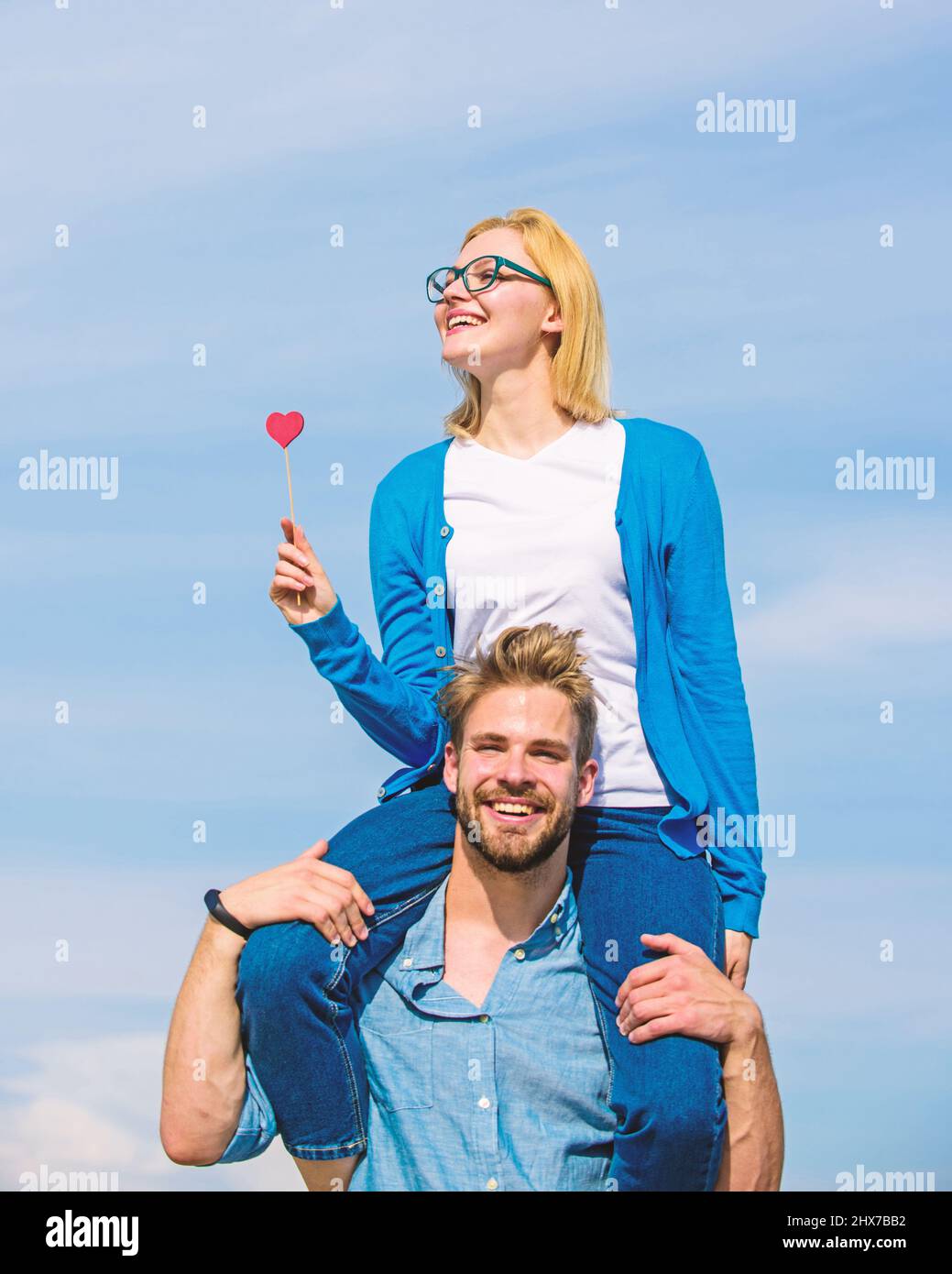 Man carries girlfriend on shoulders, sky background. Couple happy date having fun together ...