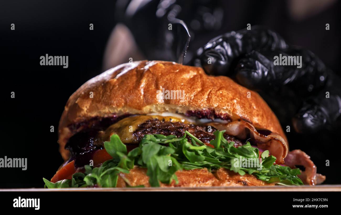 Cut craft burger is cooking on black background. Consist: sauce ...