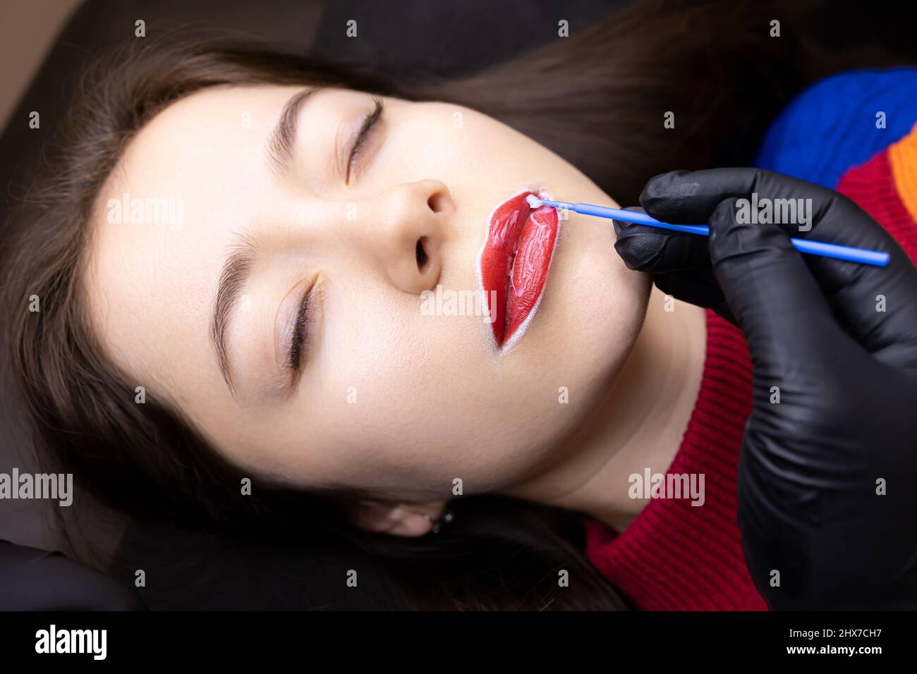 the procedure of permanent lip tattooing with black gloves is to apply ...