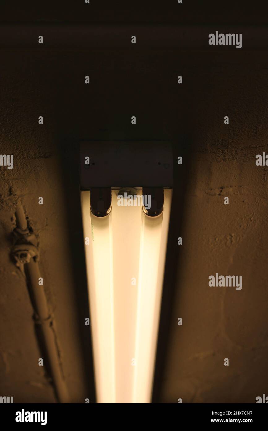 An old fluorescent ceiling light shining a pale yellow glow Stock Photo ...