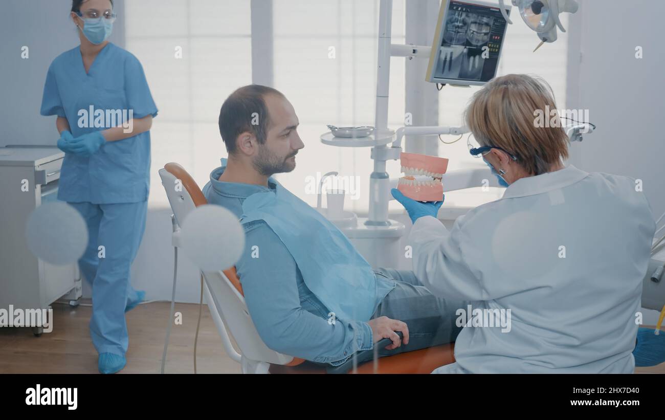 Dentist giving hygiene lesson to patient to clean teeth correctly with ...