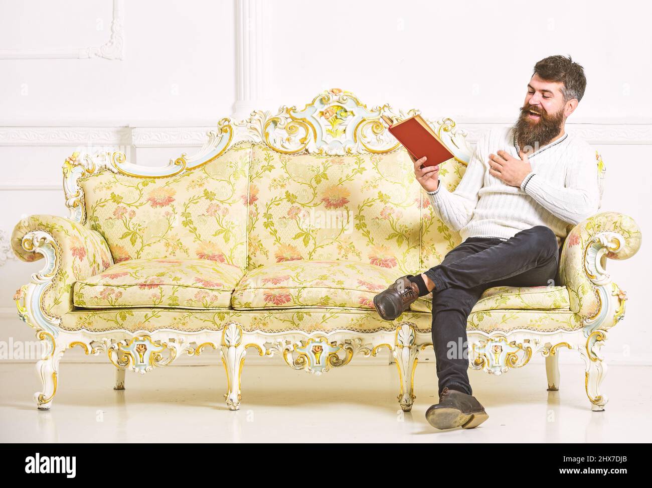 Guy reading old book with enjoyment. Man with beard and mustache sits ...