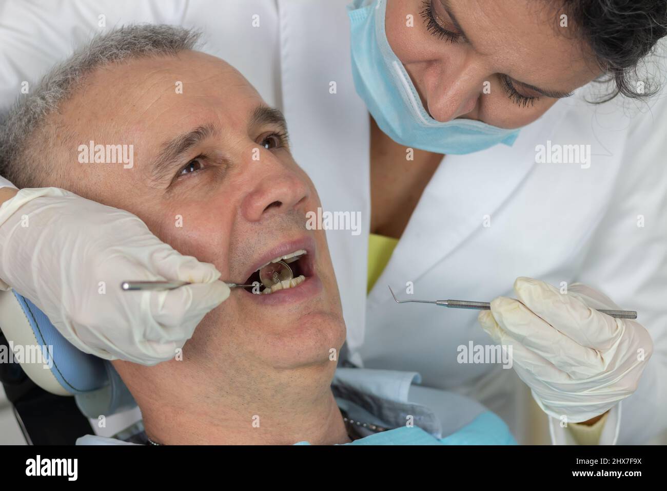 Male patient with open mouth receiving dental inspection at dentist's ...