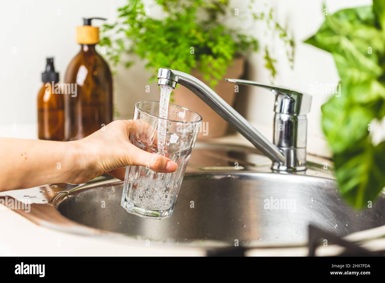 Female hand holding a glass and pouring it with tap water in the ...