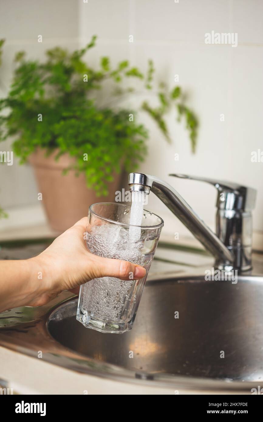 Female hand holding a glass and pouring it with tap water in the ...