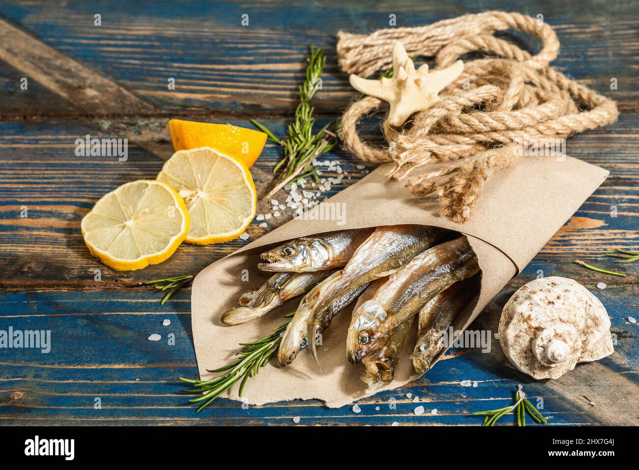 Sun-dried smelt in a paper package. Salted fish with marine decor ...