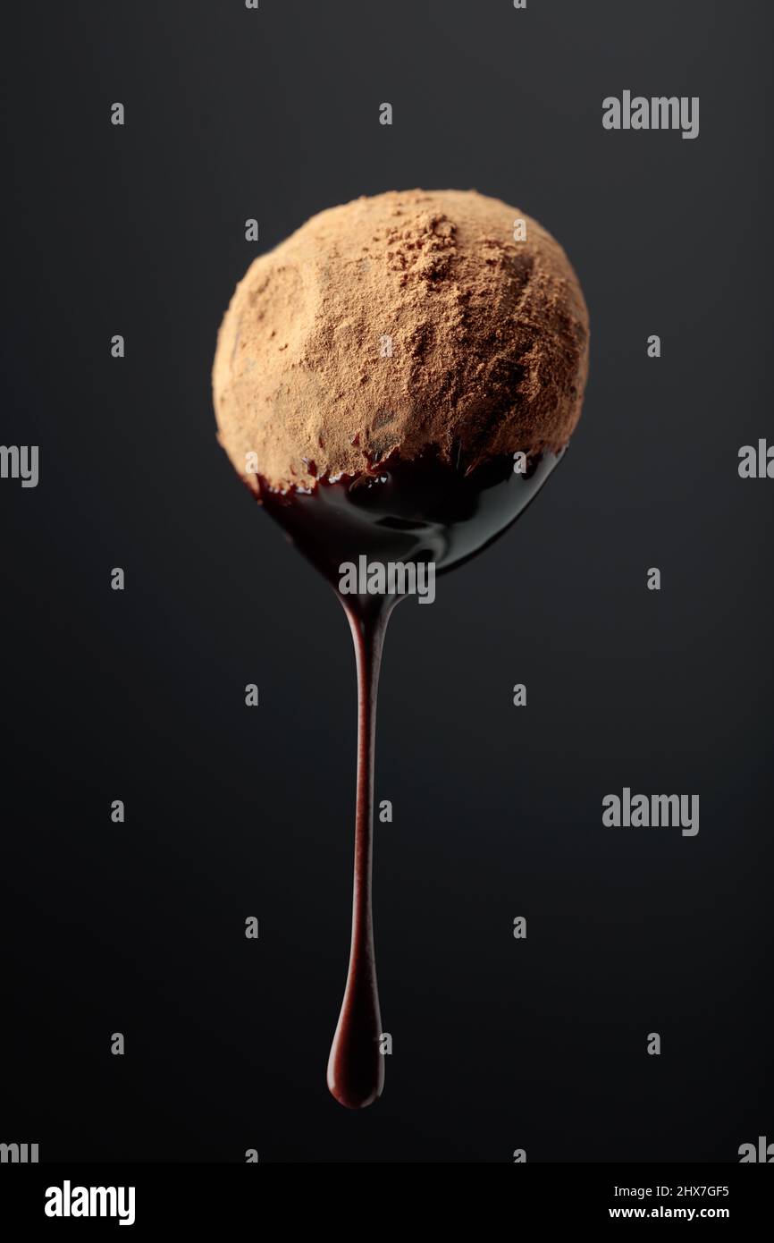 Tasty chocolate truffle and falling drop of chocolate sauce Stock Photo ...