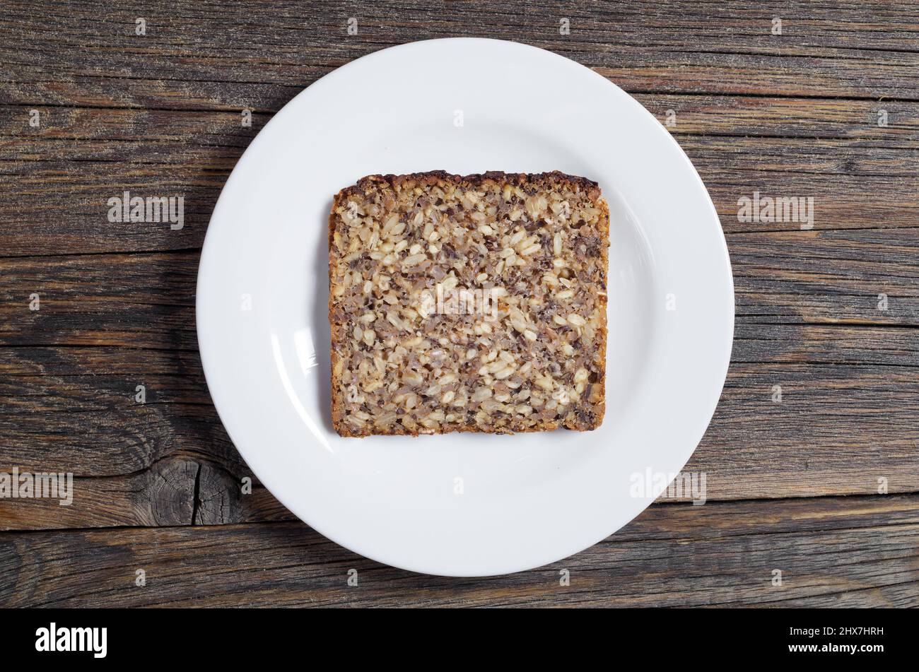 Slice of bread with different seeds in a plate on old wooden background ...