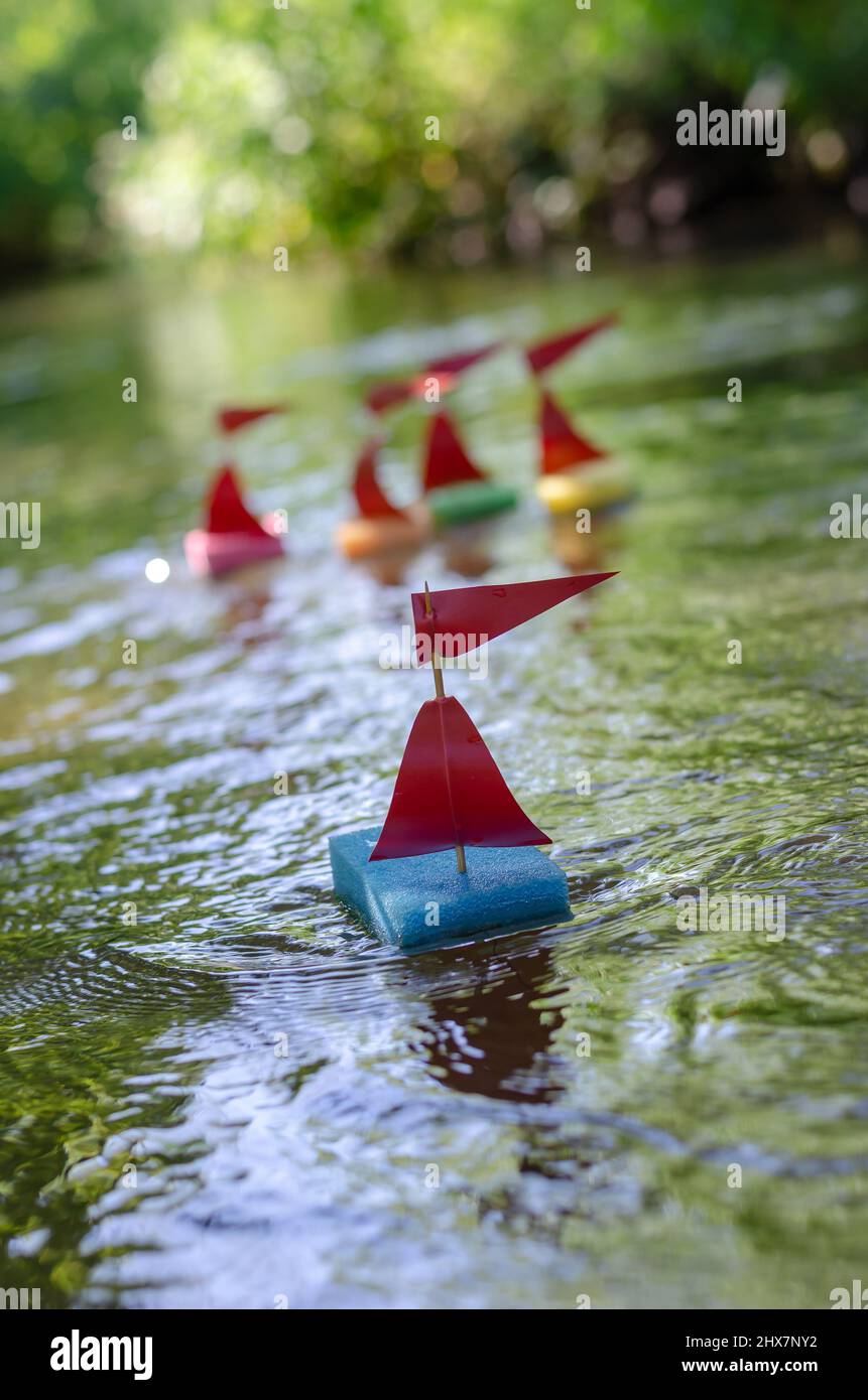 Children's boats are floating on the narrow river. Homemade mast boats ...