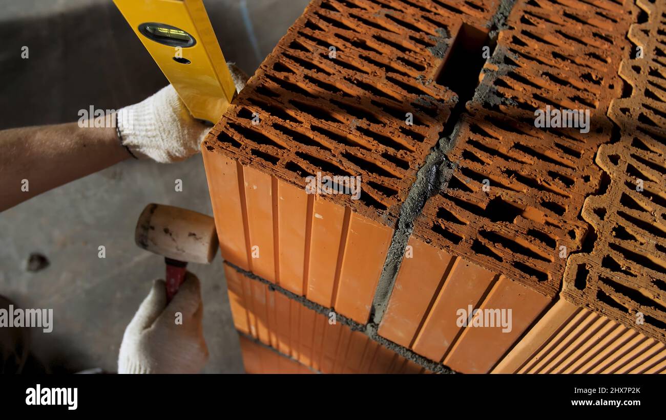 Industrial worker building exterior walls, using hammer and level for ...
