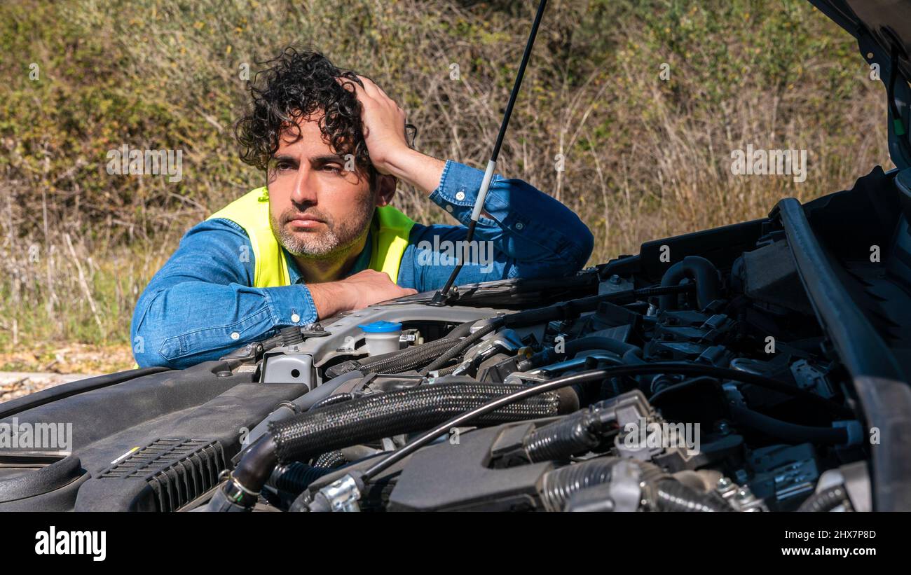 Face of unhappy male driver near a broken car with popped up hood ...