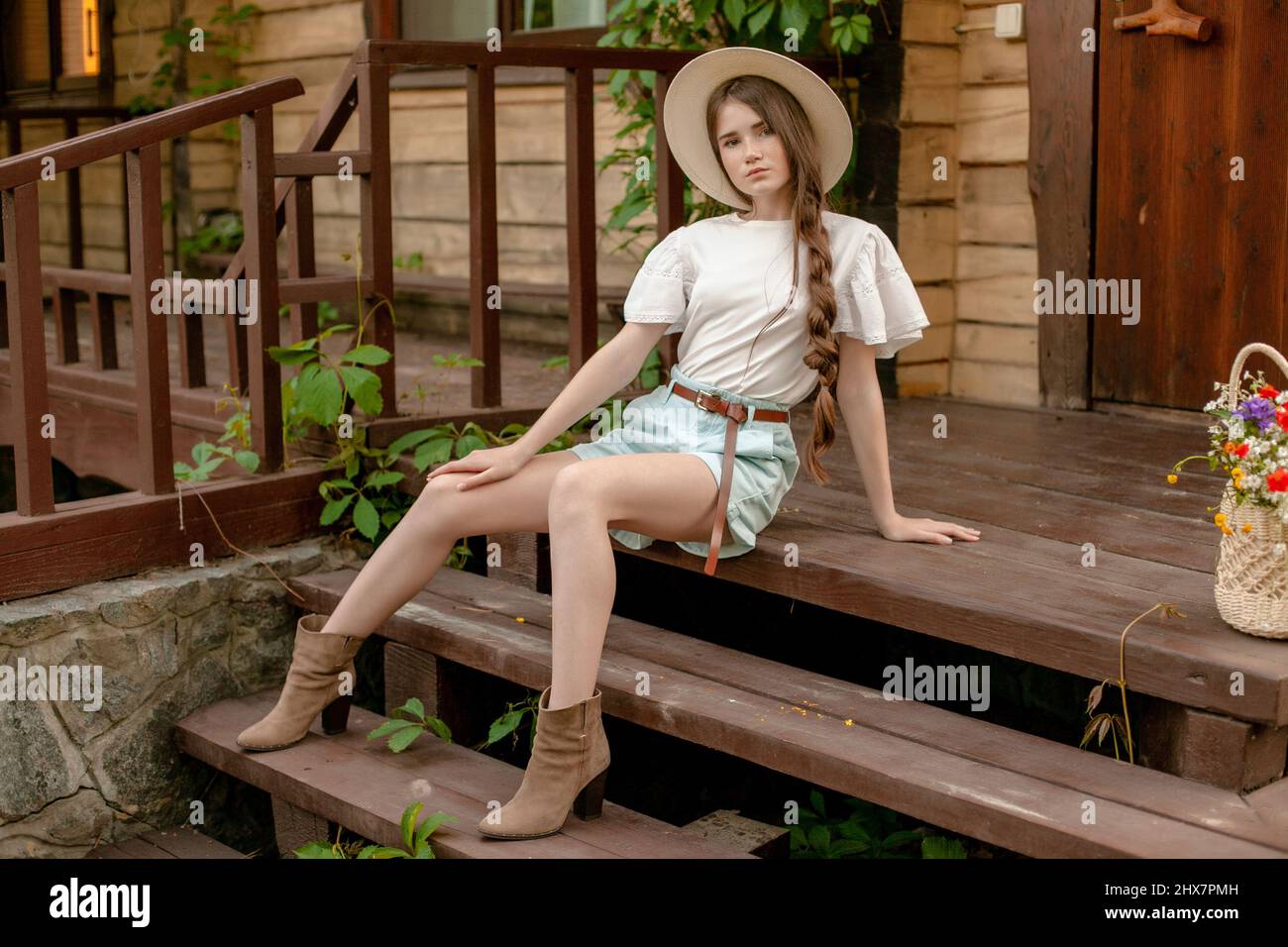 Brown-haired tween girl sitting on wooden doorstep of country house in ...