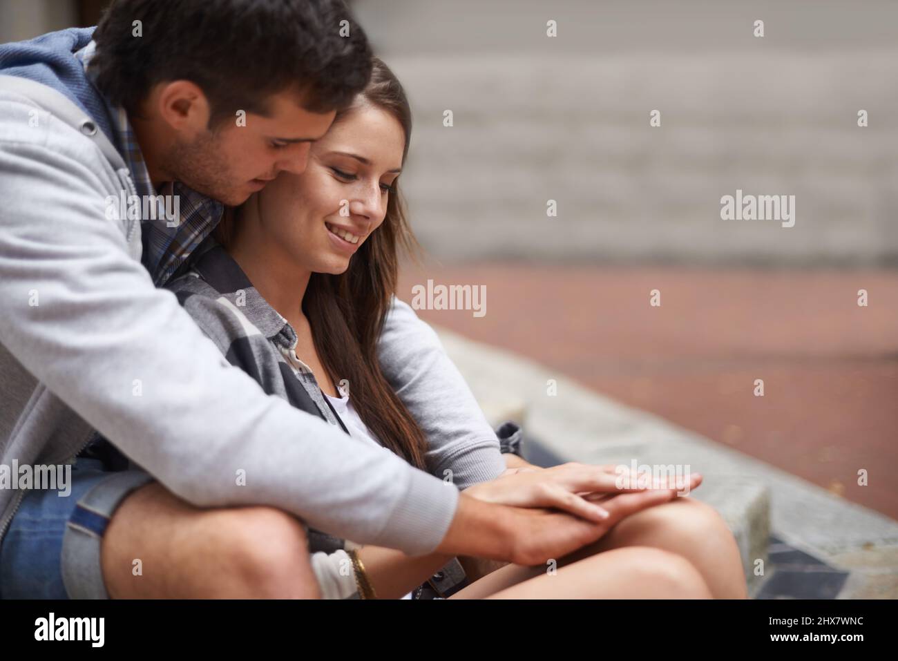 Sharing an intimate moment. A happy young couple sitting outside having ...