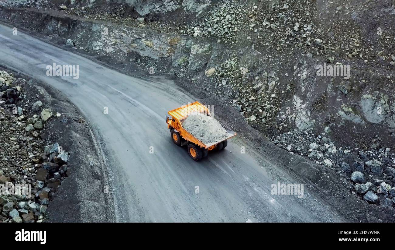 Dump truck is at quarry. Top view of driving orange dump truck with ...