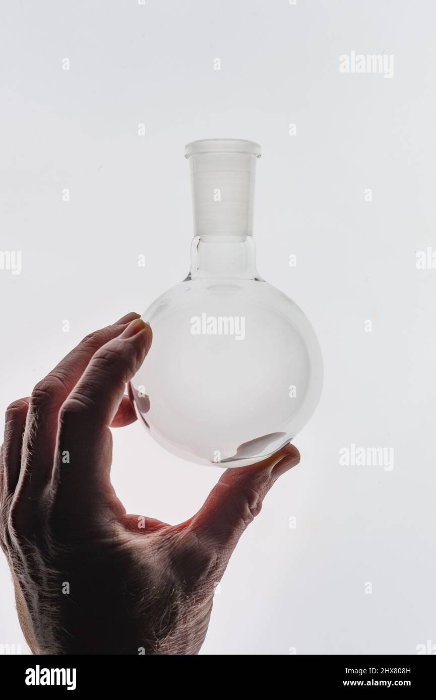 Hand holding clear empty glass flask white background Stock Photo - Alamy