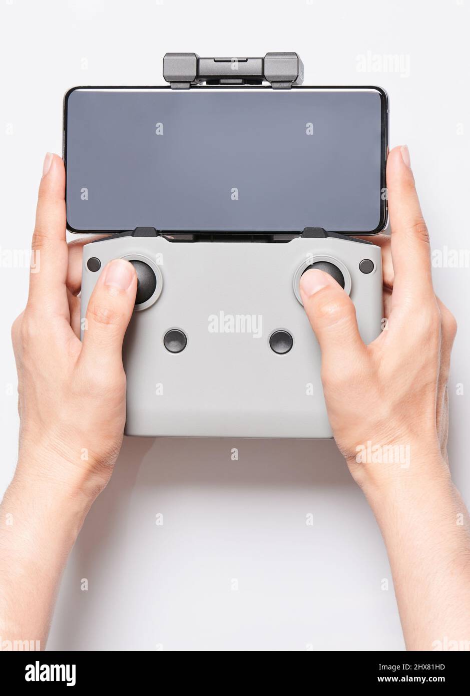 Remote controller with smartphone in hands isolated on studio ...