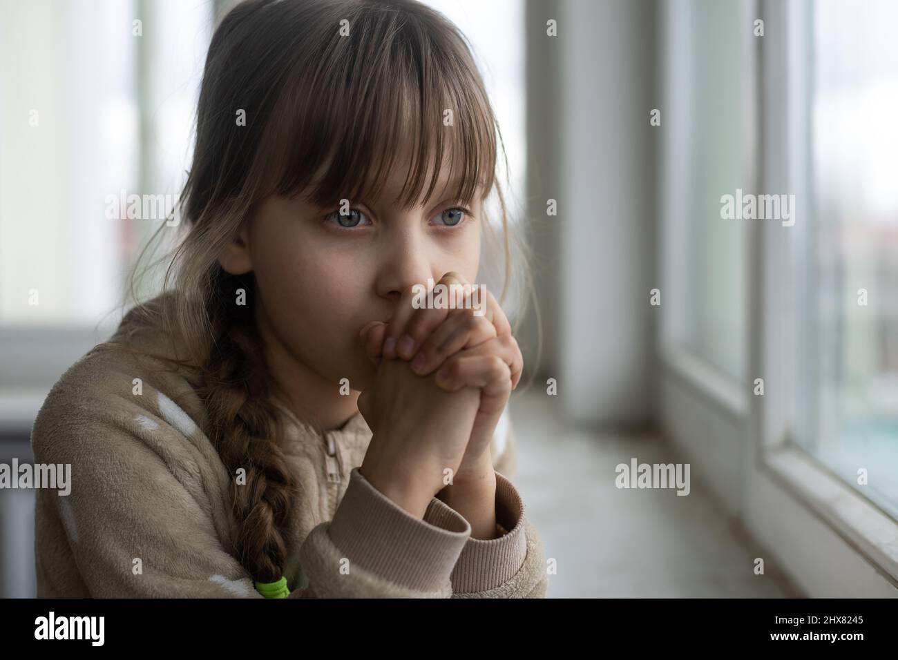 Praying little girl near window Stock Photo - Alamy