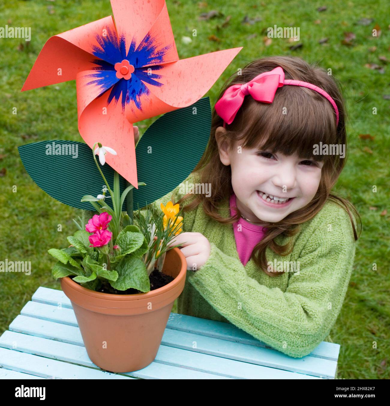 Girl in the garden with homemade paper windmill flower in plant pot ...