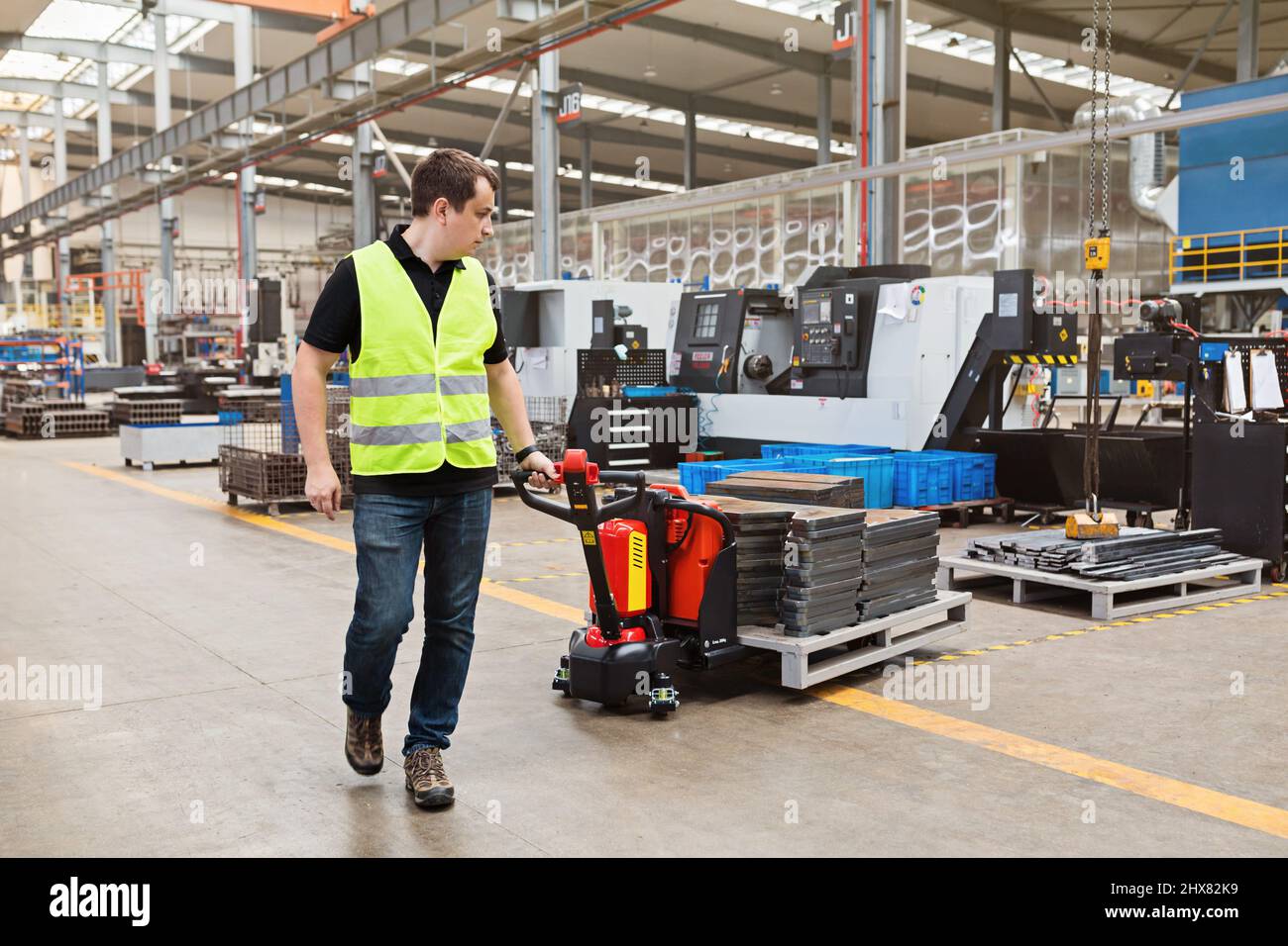 Warehouse worker dragging hand pallet truck or manual forklift with the ...