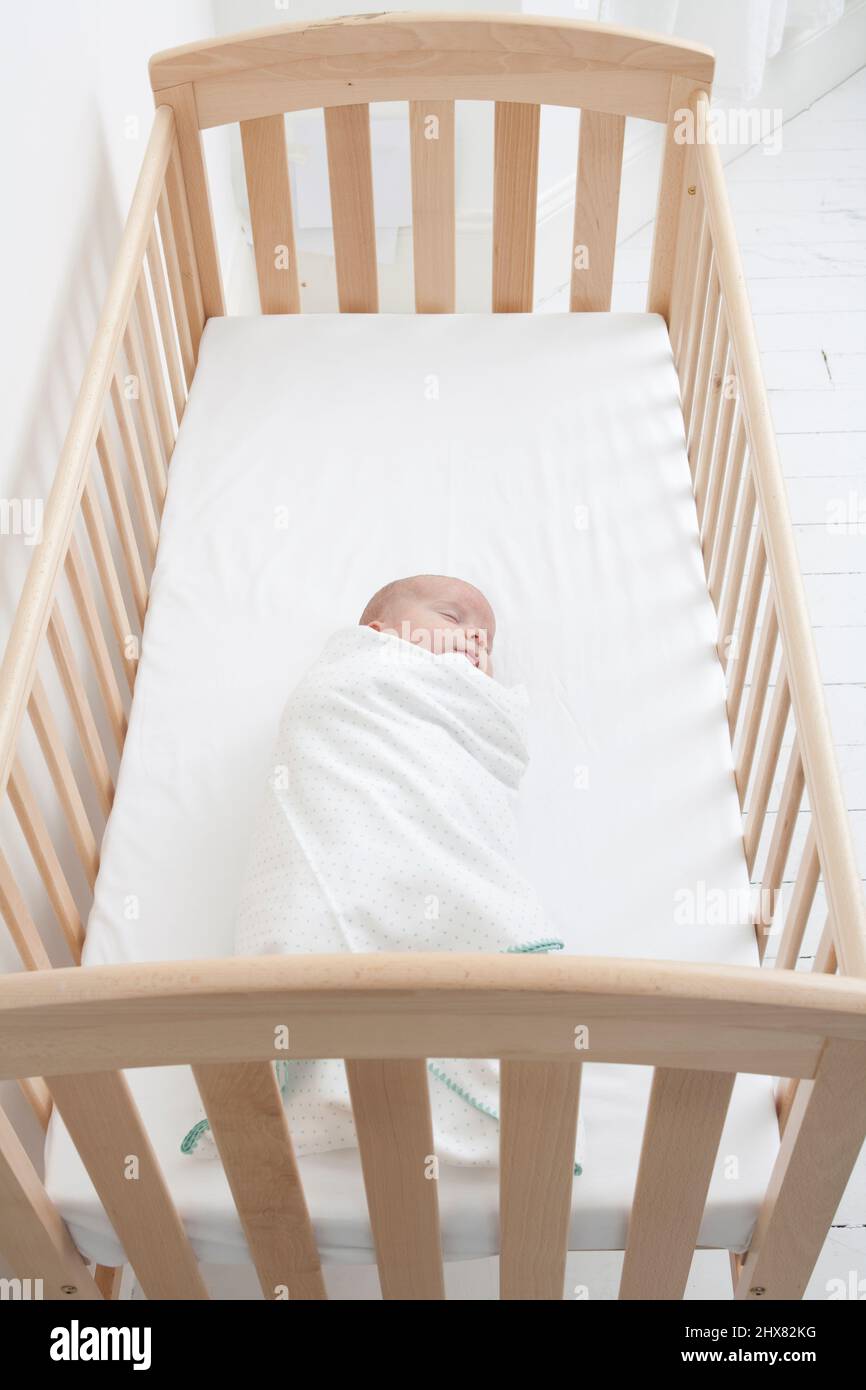 Swaddled sleeping baby in a cot Stock Photo - Alamy