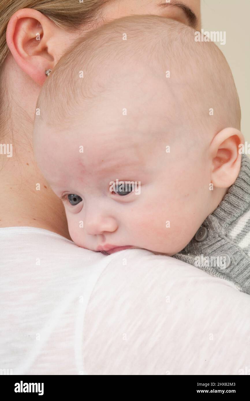 Mother holding tiny drowsy baby boy against one shoulder, close-up ...
