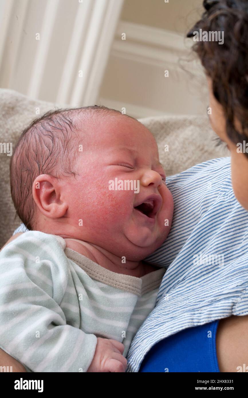 Baby boy cradled in mother's arms with mouth open, close-up Stock Photo ...