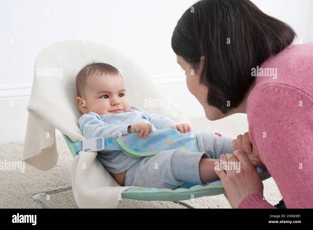 Baby boy strapped into baby chair covered in a soft blanket with his ...