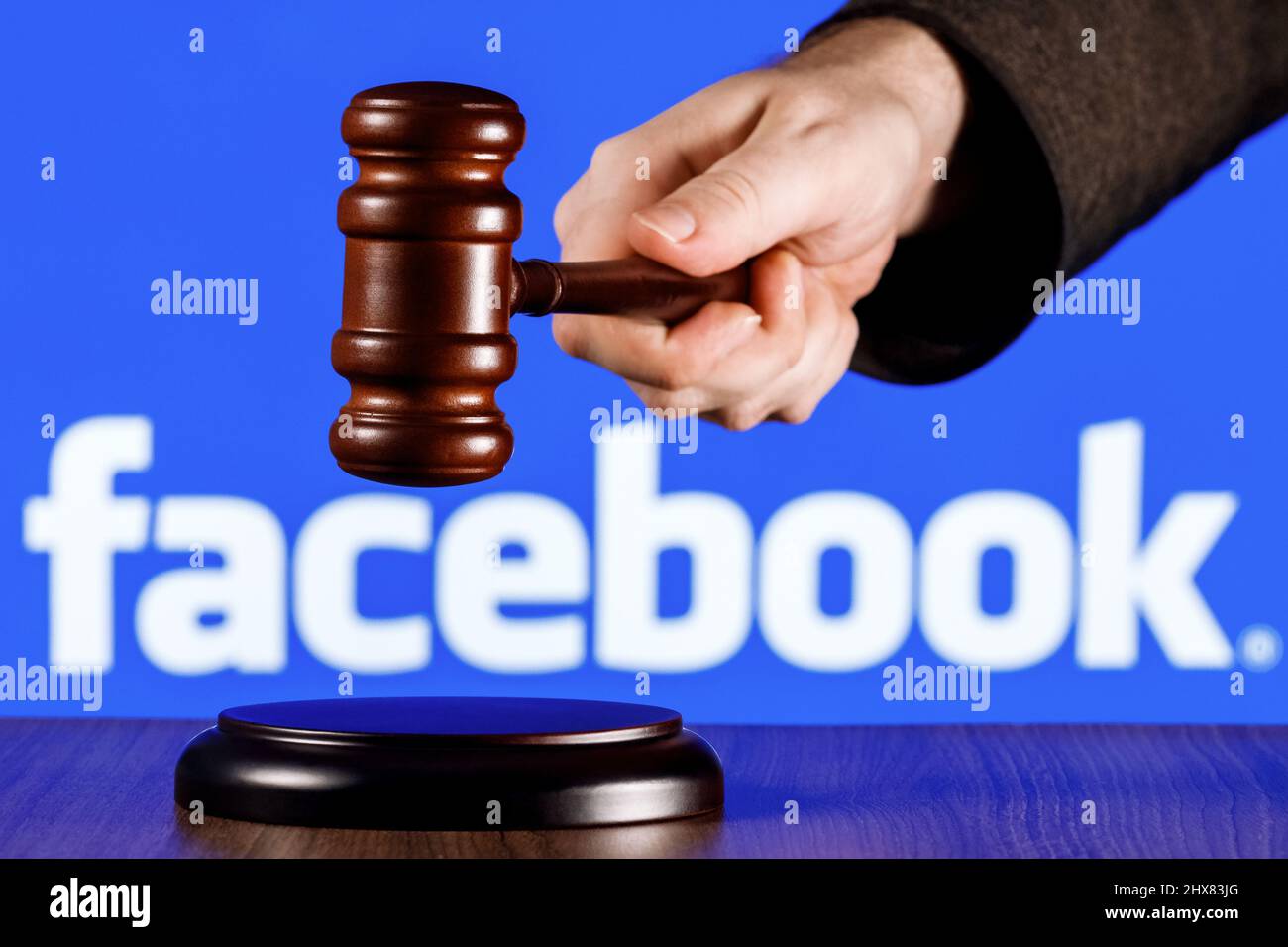 Gavel in judge hand against background of Facebook social network logo ...