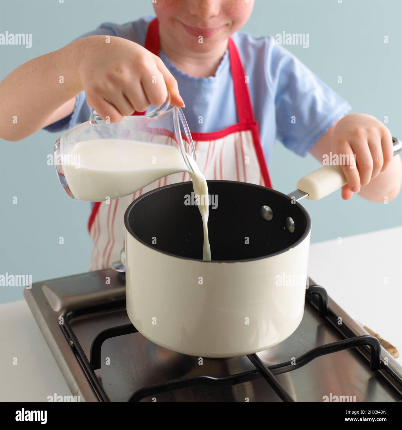Child pouring milk in saucepan on gas hob Stock Photo - Alamy