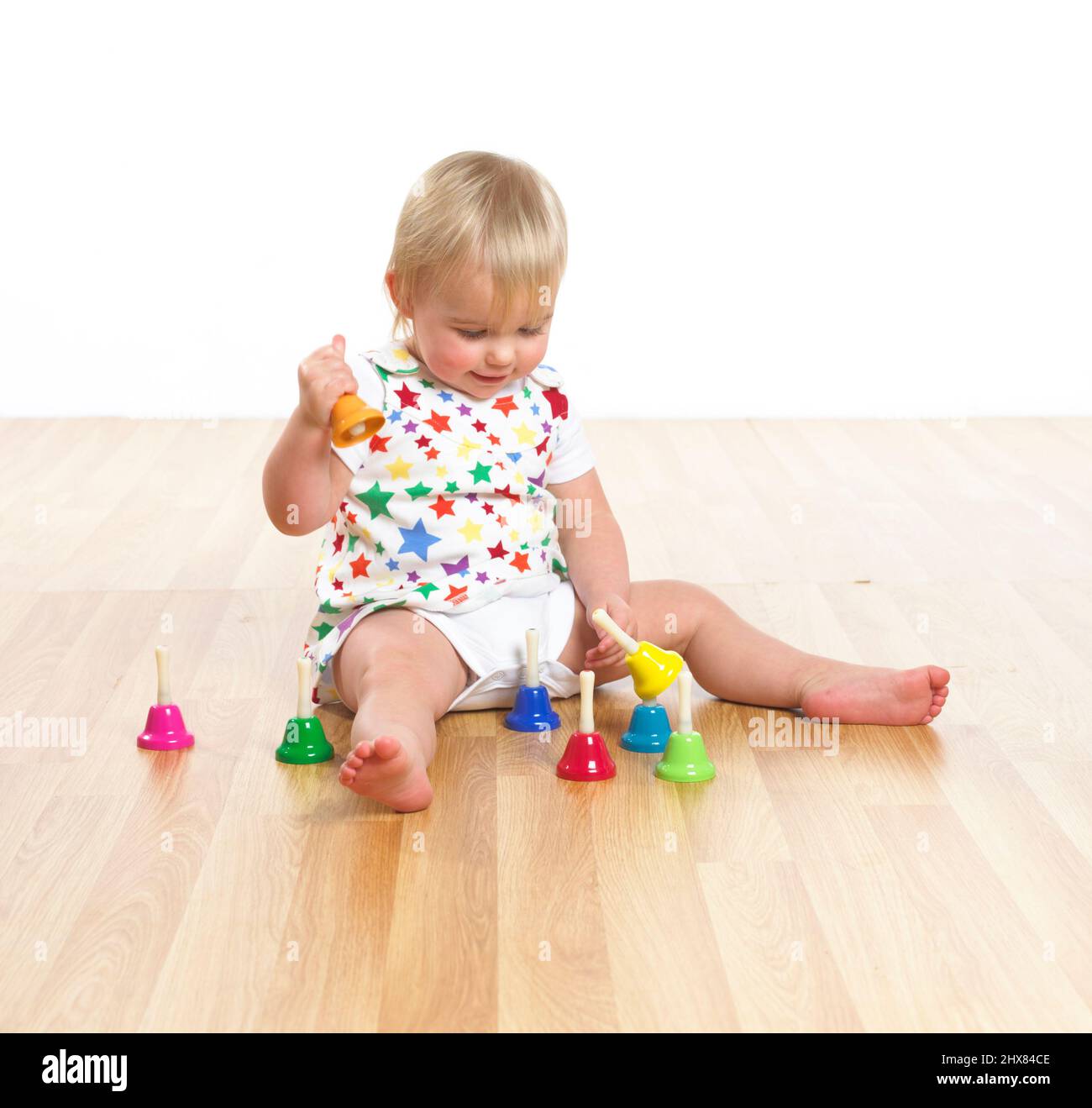 Toddler sitting on floor playing with plastic bells Stock Photo - Alamy