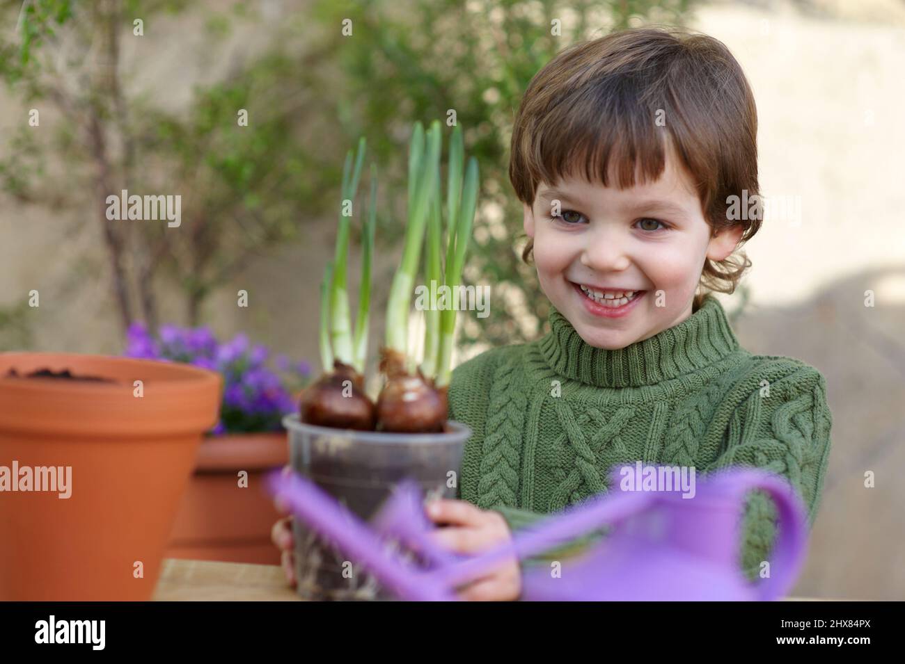 Boy holding pot plant and smiling Stock Photo - Alamy