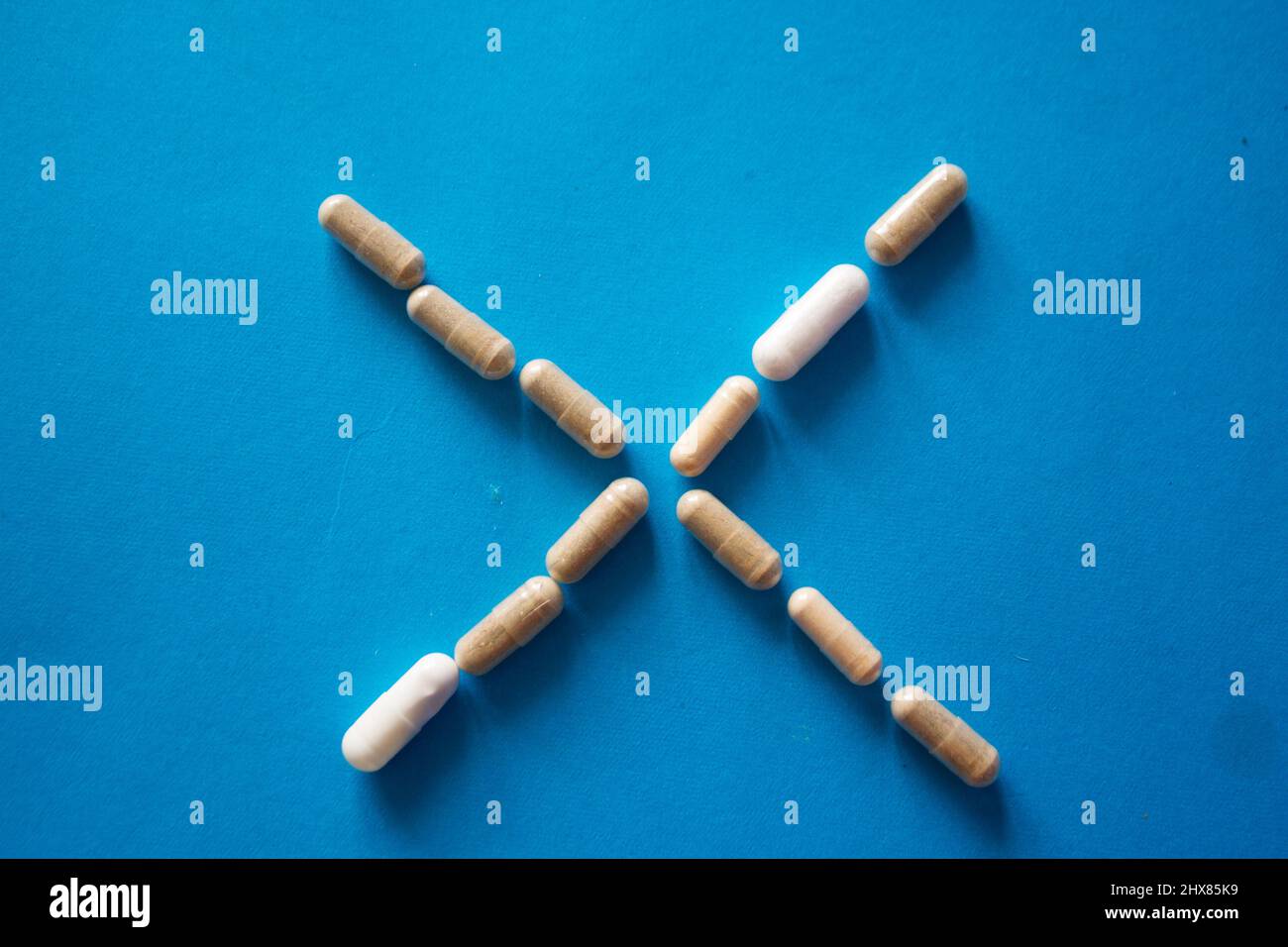 Cross made of pills on blue background. Trying to stop an addiction ...